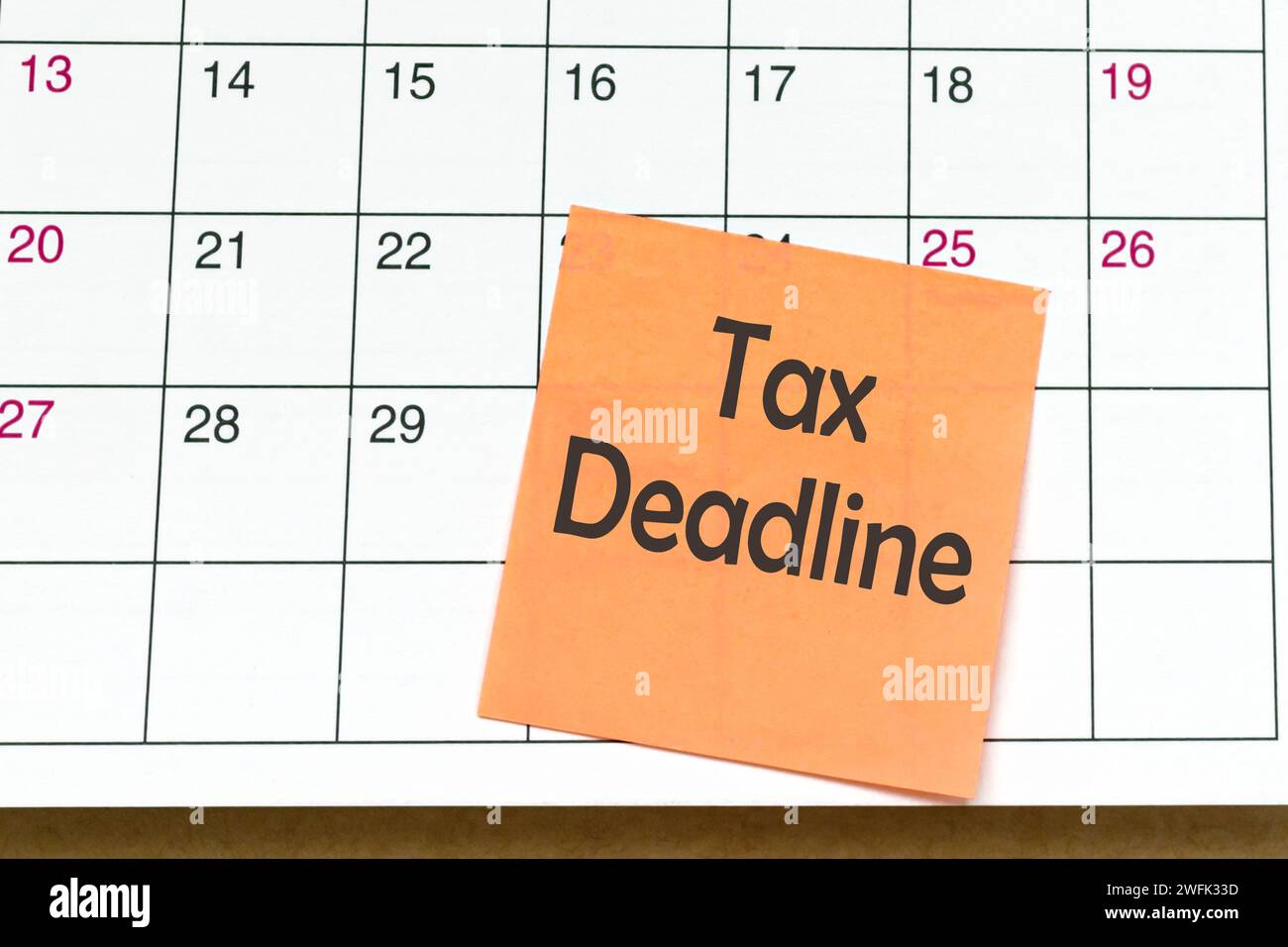 Tax deadline text on orange paper sticky note and stuck to a calendar ...