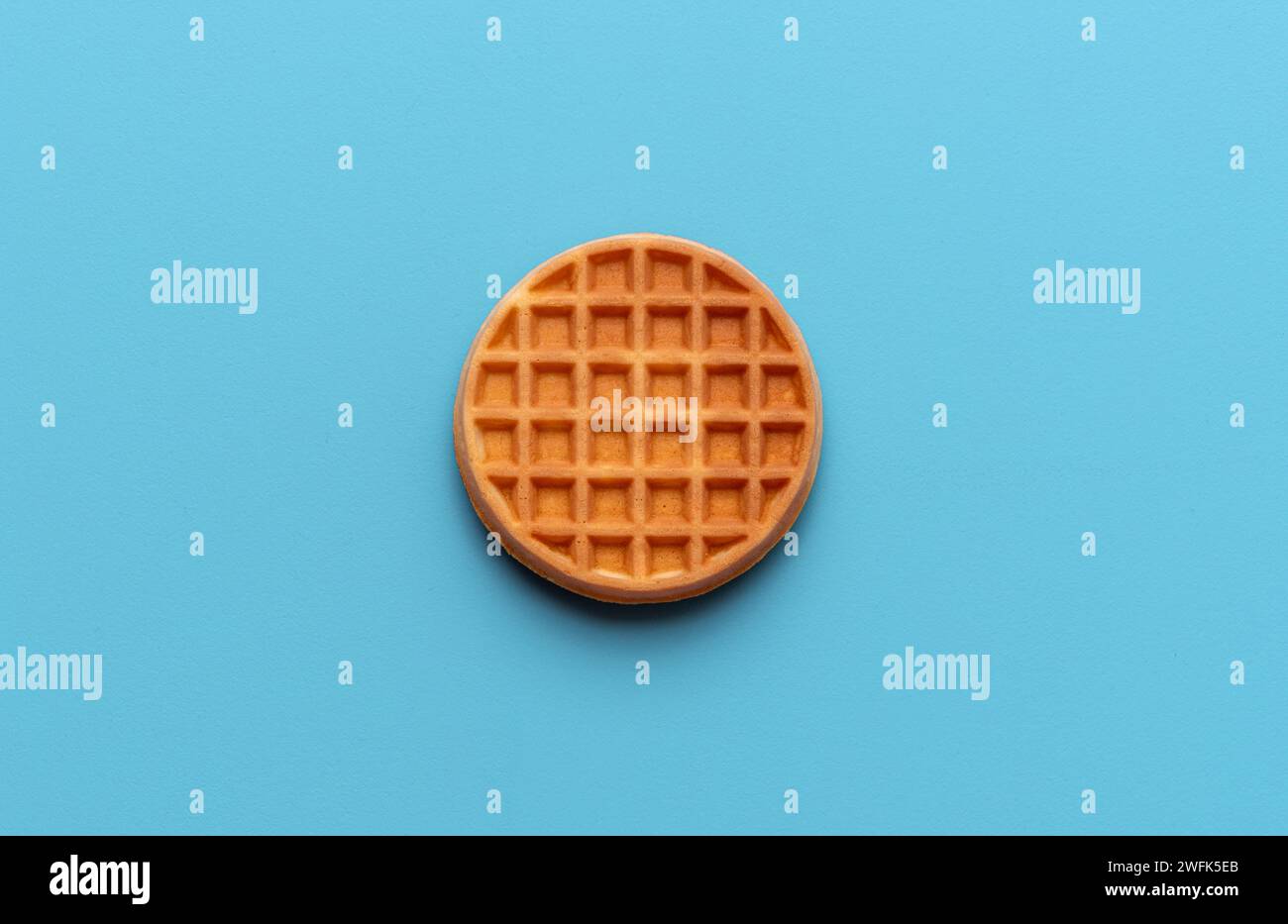 Top view with a single round belgian waffle minimalist on a blue ...