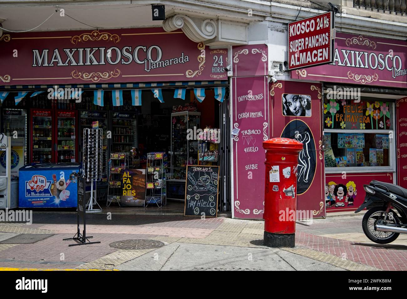 A colourful 24hr local shop font selling sweets and soft drinks. A ...