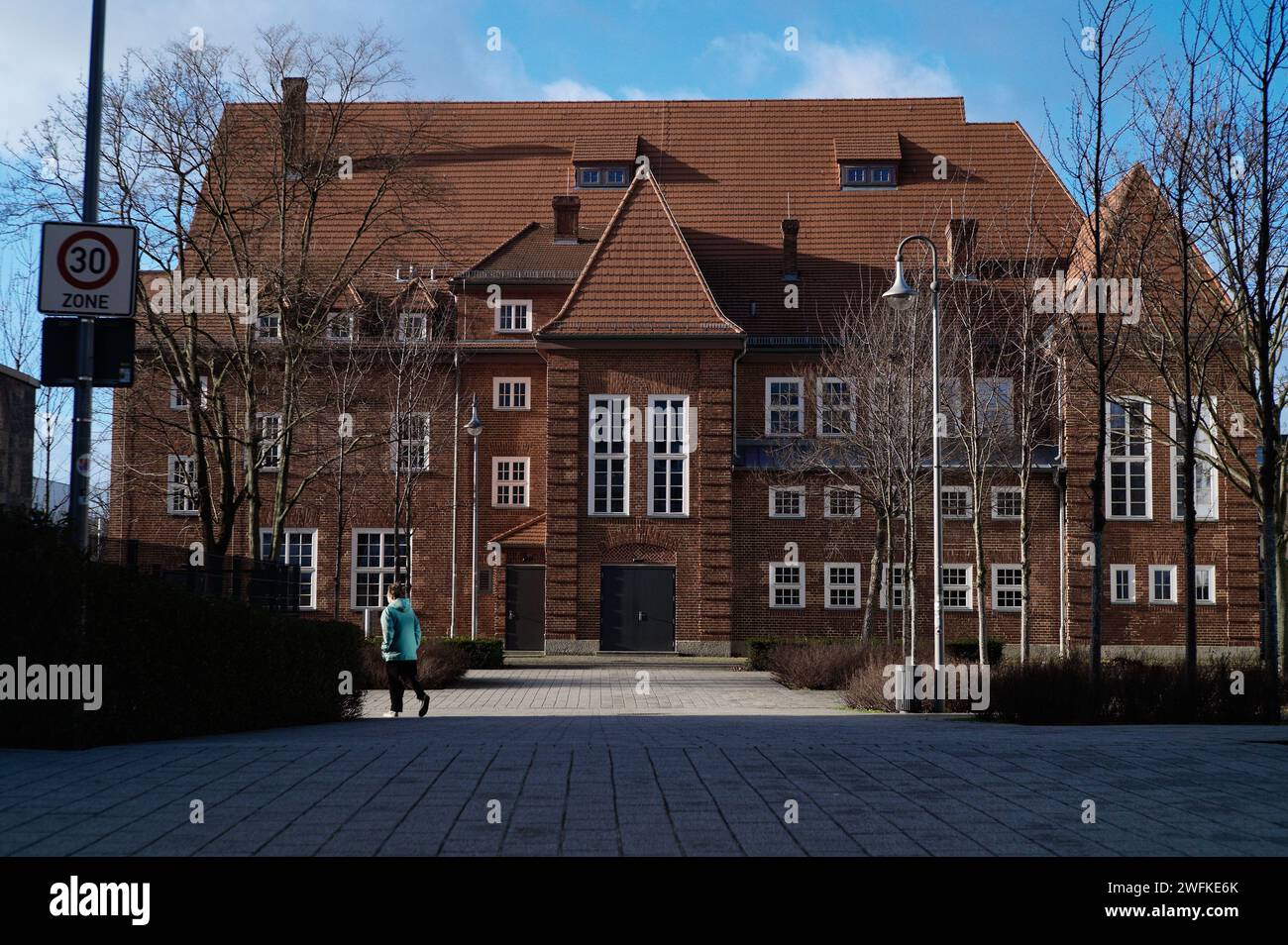 An aged brick building with pedestrians passing by in the foreground ...