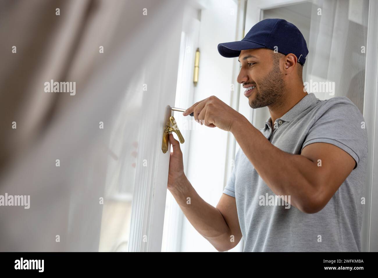 Attractive man fixing window handle with screw Stock Photo - Alamy