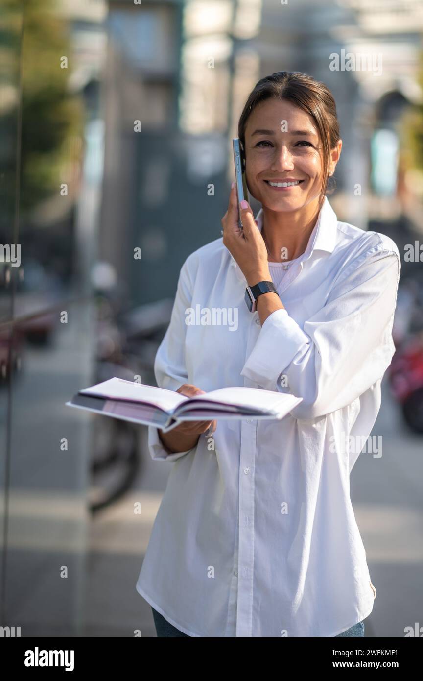 Cute woman talking on the phone and looking interested Stock Photo - Alamy