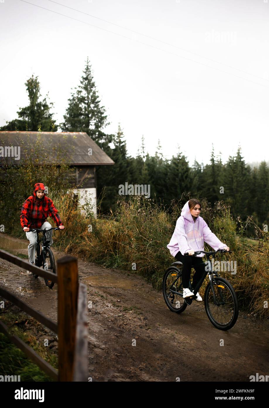 Biker couple riding mountain bike in the forest at countryside. rainy ...