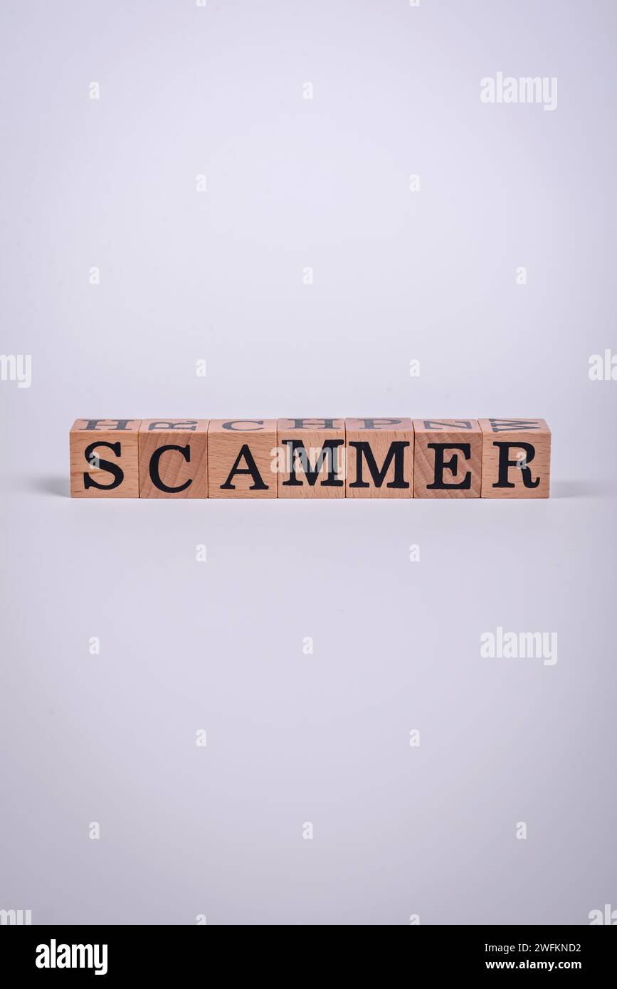 The inscription Scammer made of wooden cubes on a plain background. Can ...