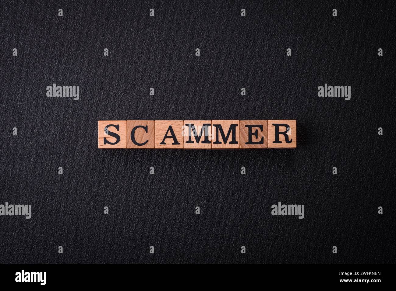 The inscription Scammer made of wooden cubes on a plain background. Can ...