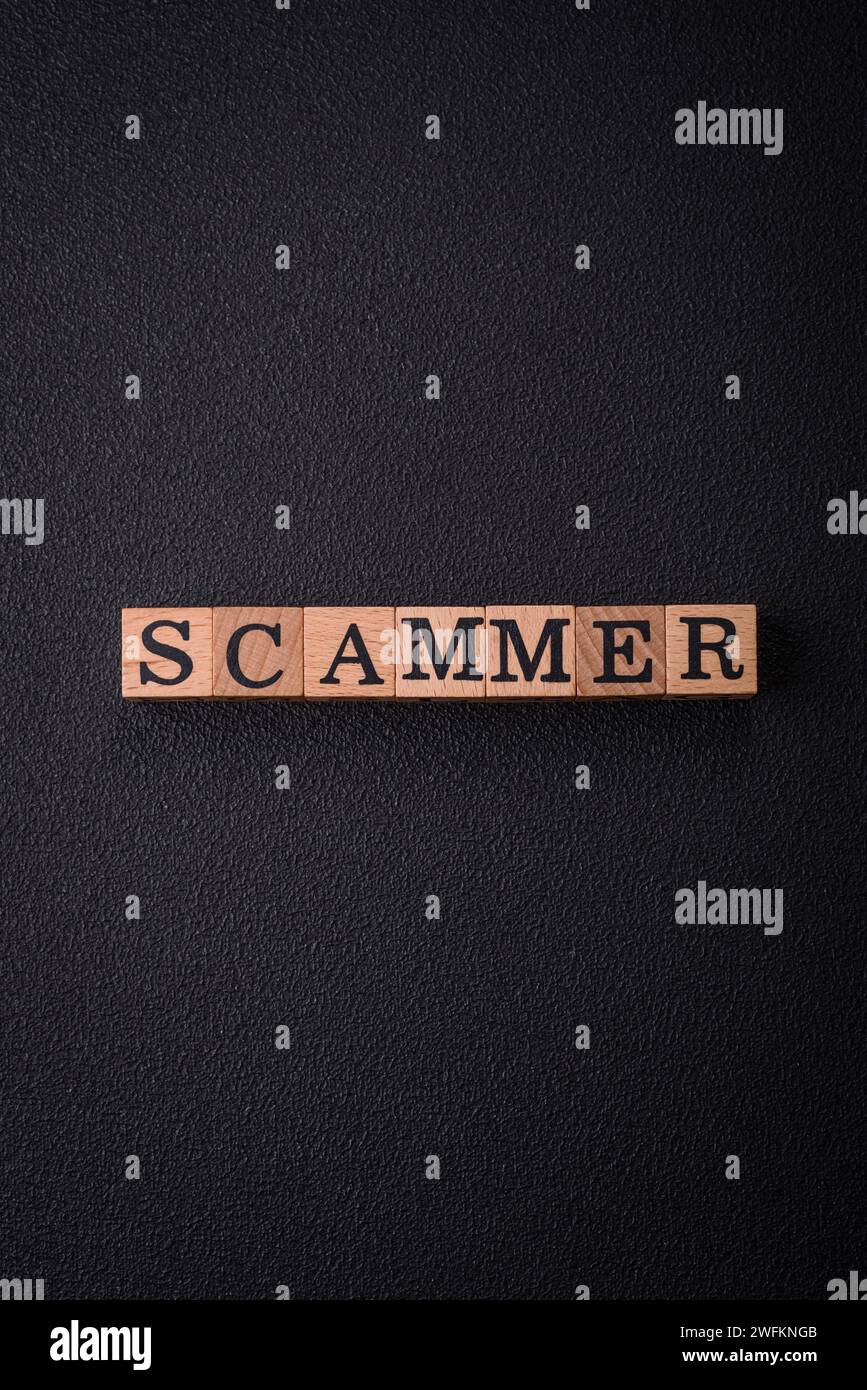 The inscription Scammer made of wooden cubes on a plain background. Can ...
