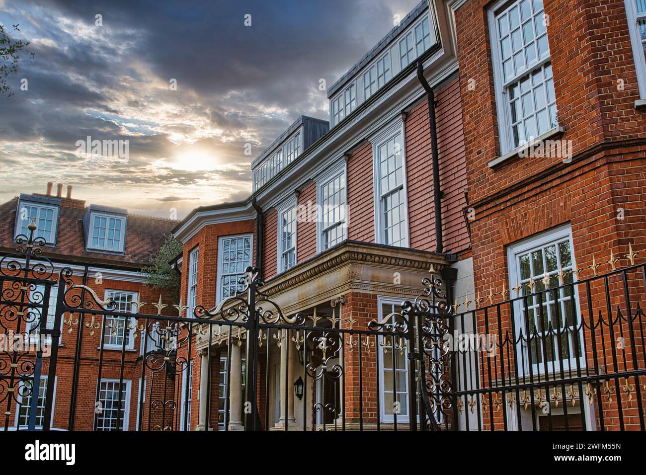 Elegant brick building with large windows behind ornate iron gates ...