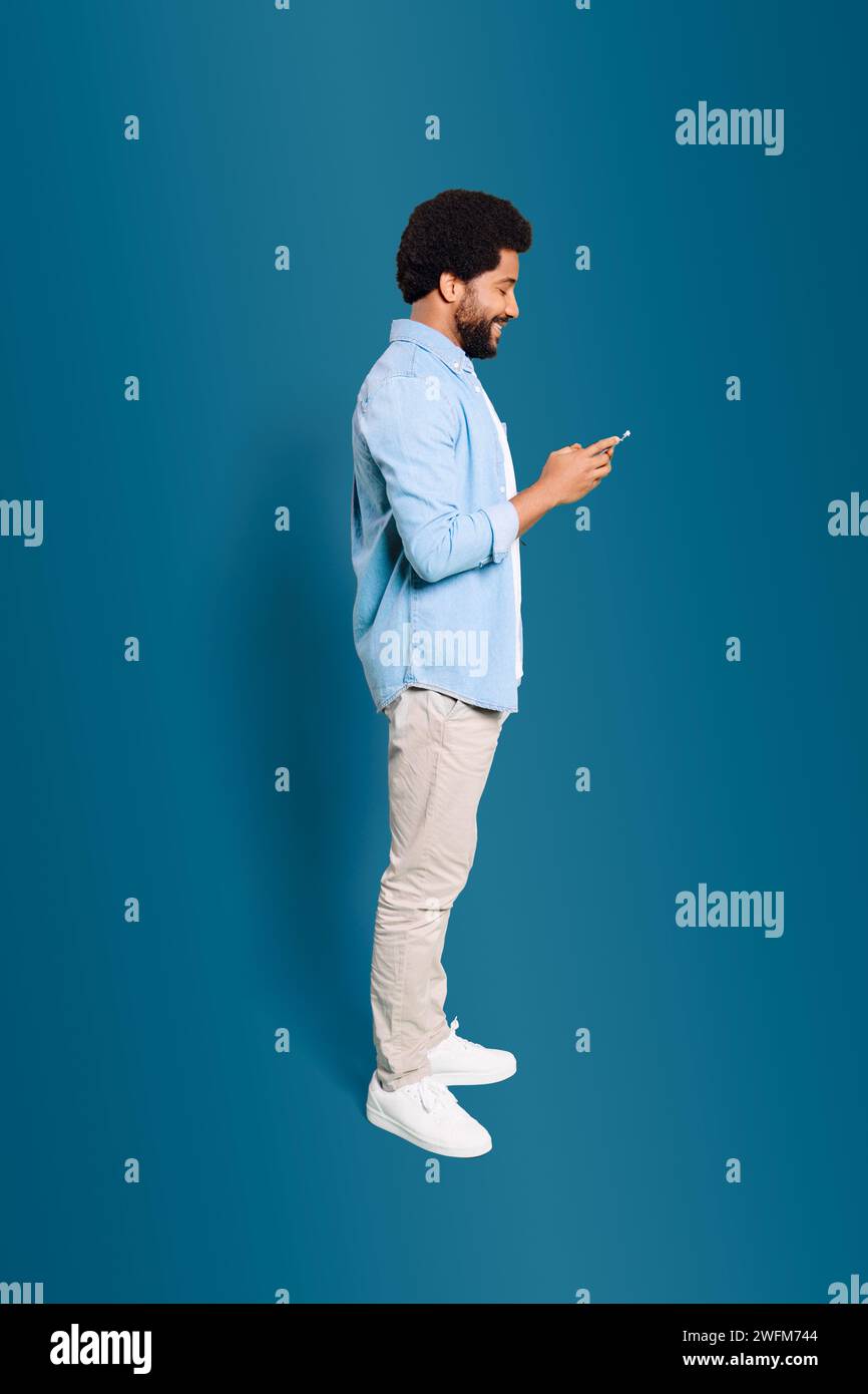 A young man in profile, deeply engaged with his phone, illustrating the ...