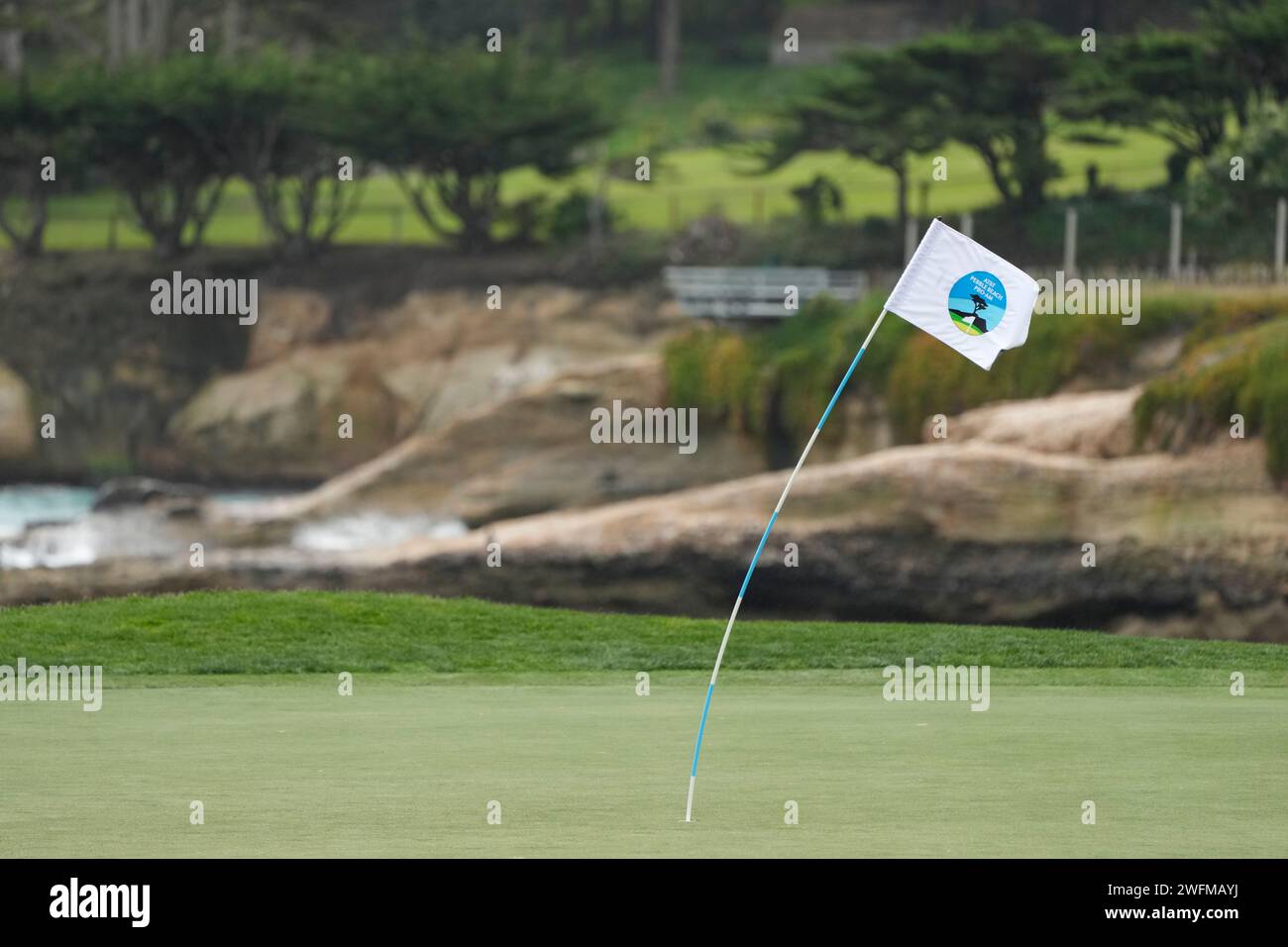 A flagstick on the 18th green of the Pebble Beach Golf Links bends in ...