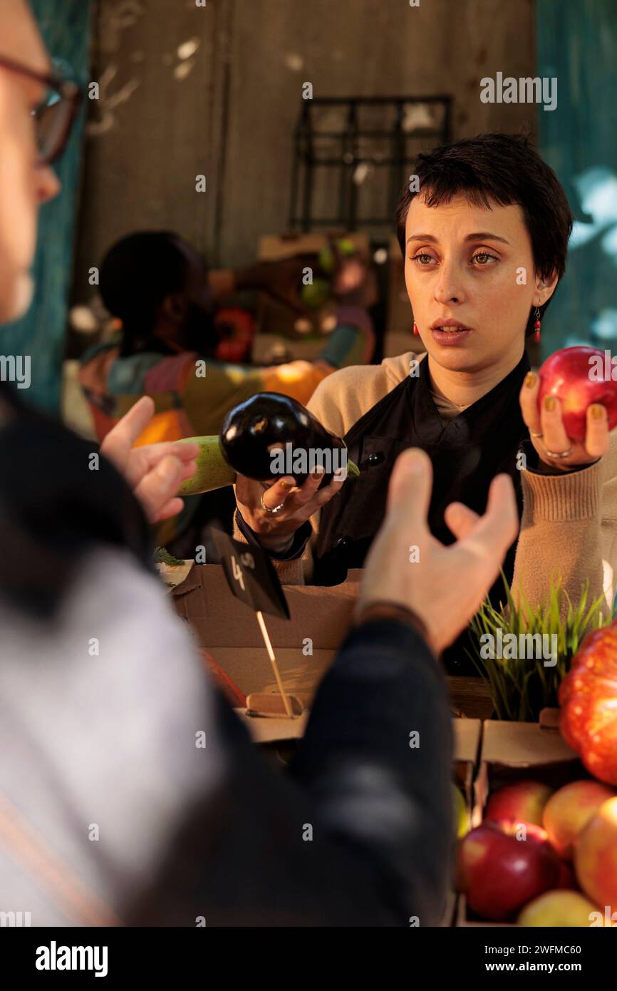 Food market owner standing behind stand and serving customer, selling ...
