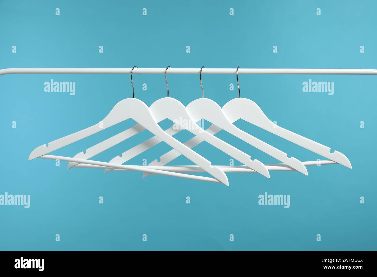 Empty clothes hangers on rack against light blue background Stock Photo ...