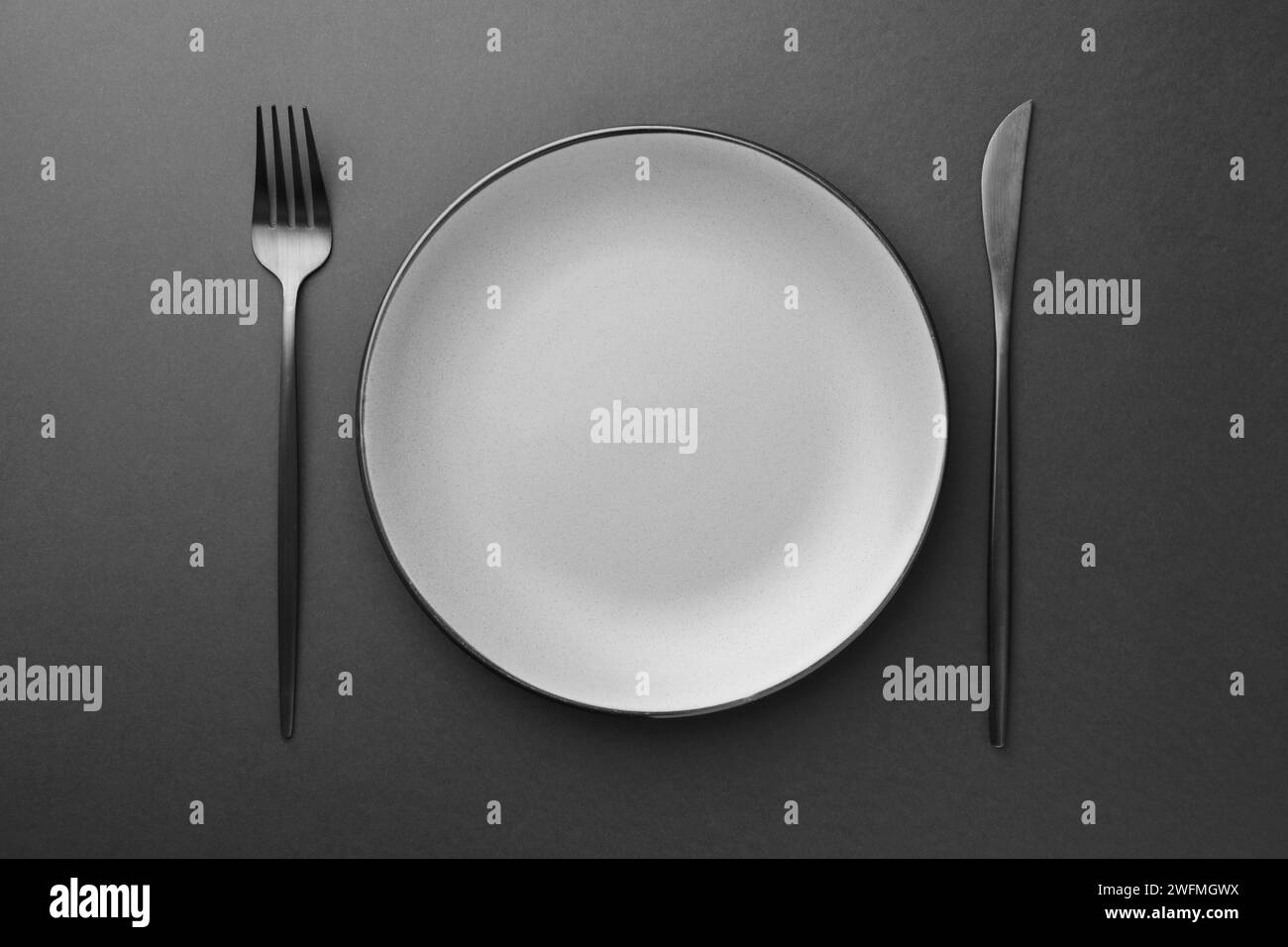 Empty plate, fork and knife on grey table, top view Stock Photo - Alamy