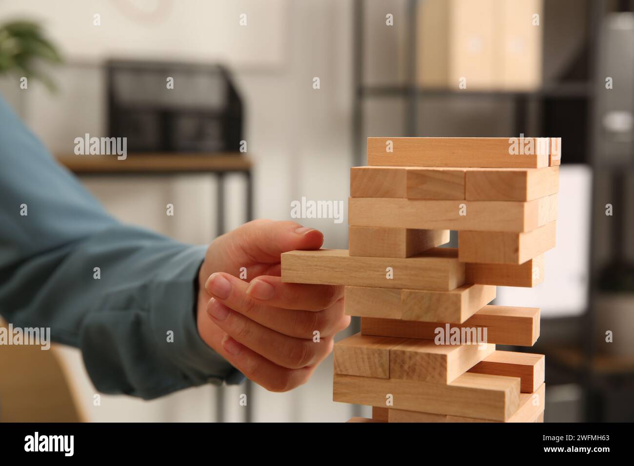 Playing Jenga. Woman removing wooden block from tower indoors, closeup ...