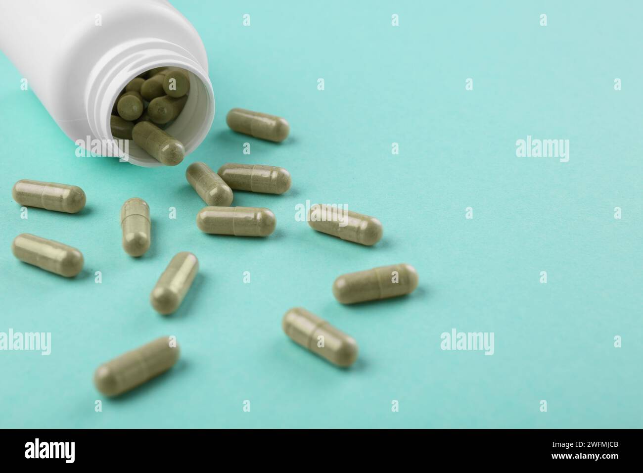 Bottle and vitamin capsules on turquoise background, closeup. Space for ...