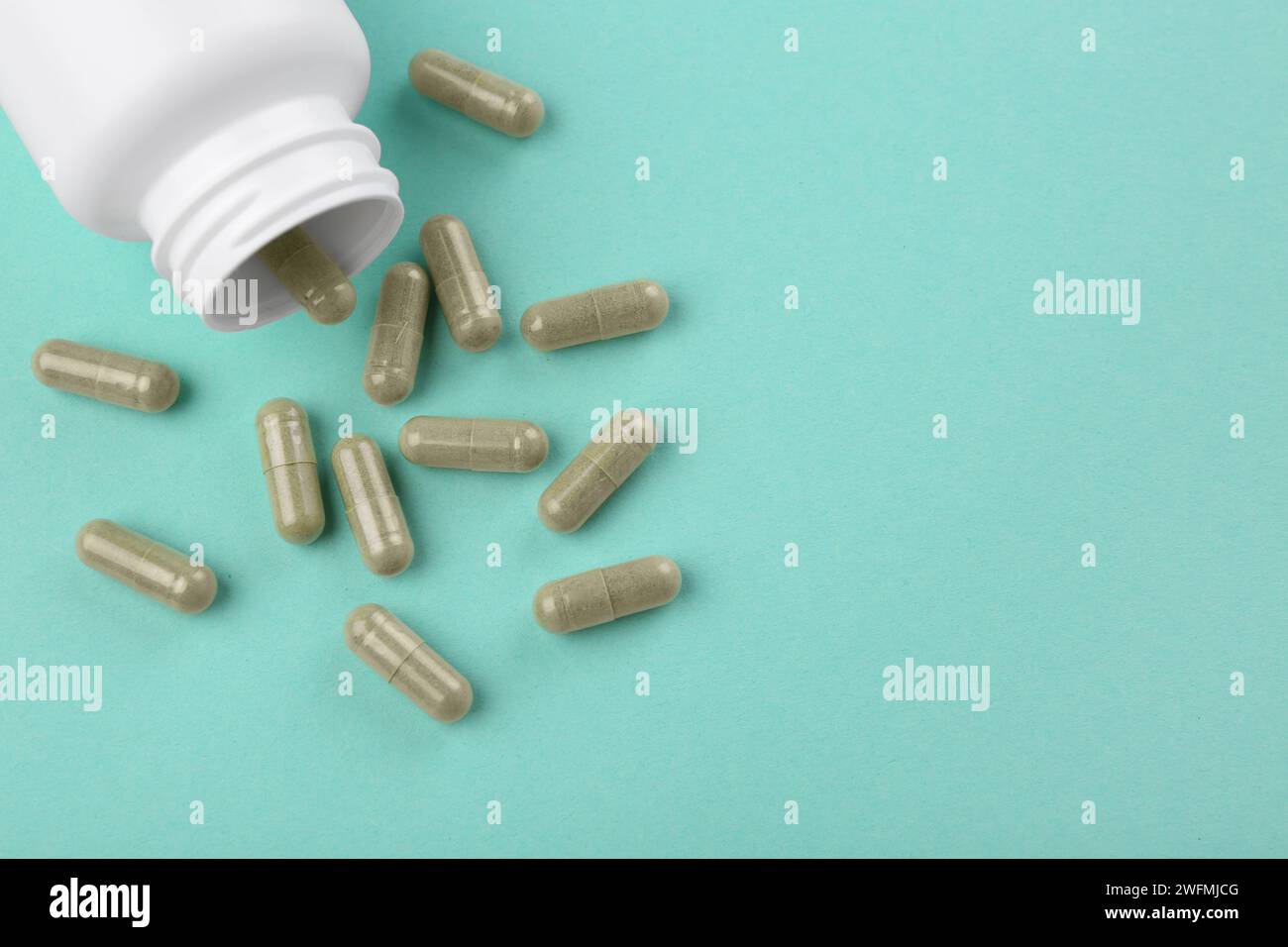 Bottle and vitamin capsules on turquoise background, top view. Space ...