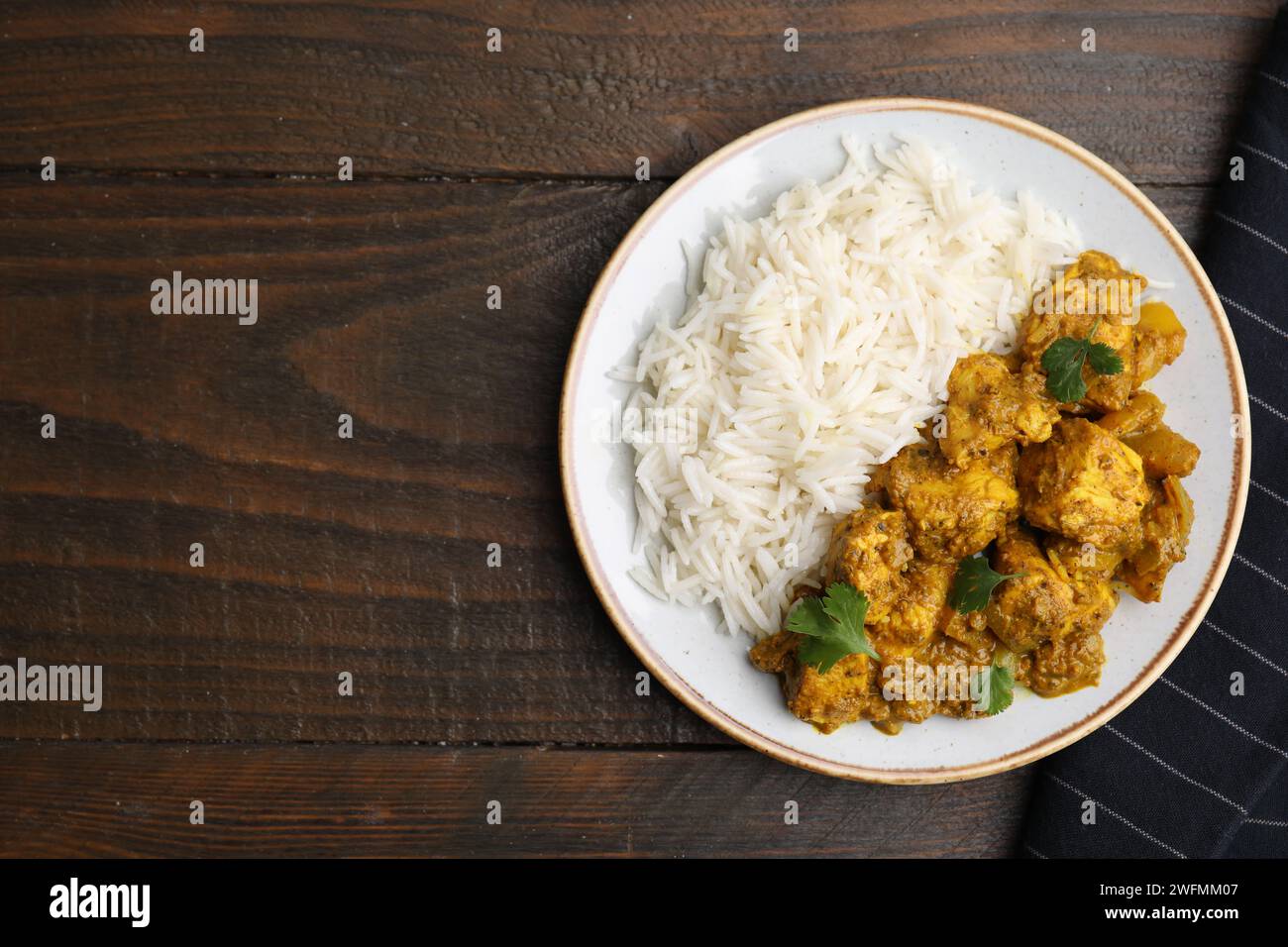 Delicious chicken curry with rice on wooden table, top view. Space for ...