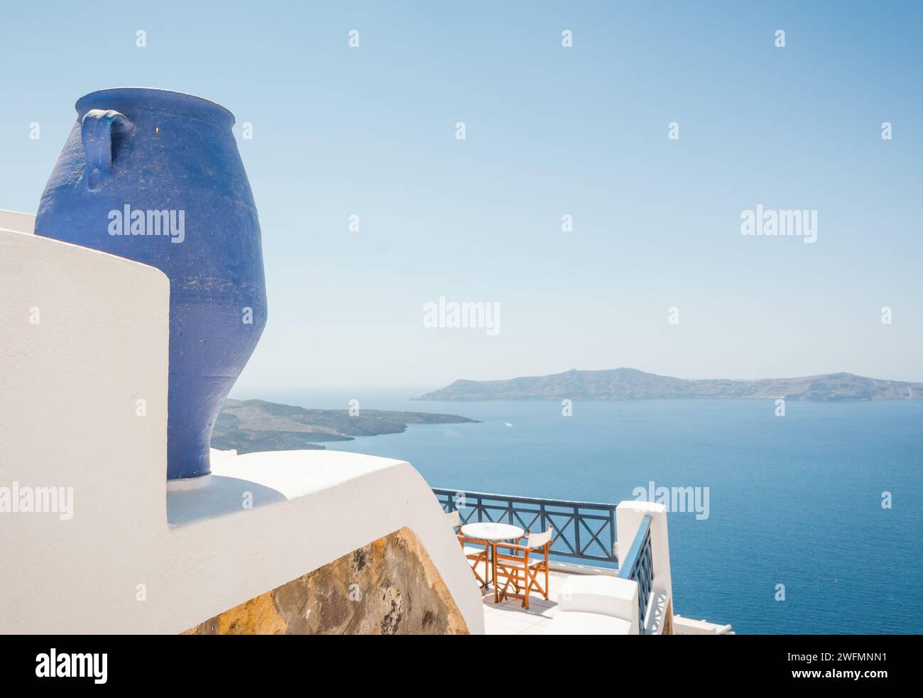 blue vase, table with two chairs on the cliff of Santorini island ...