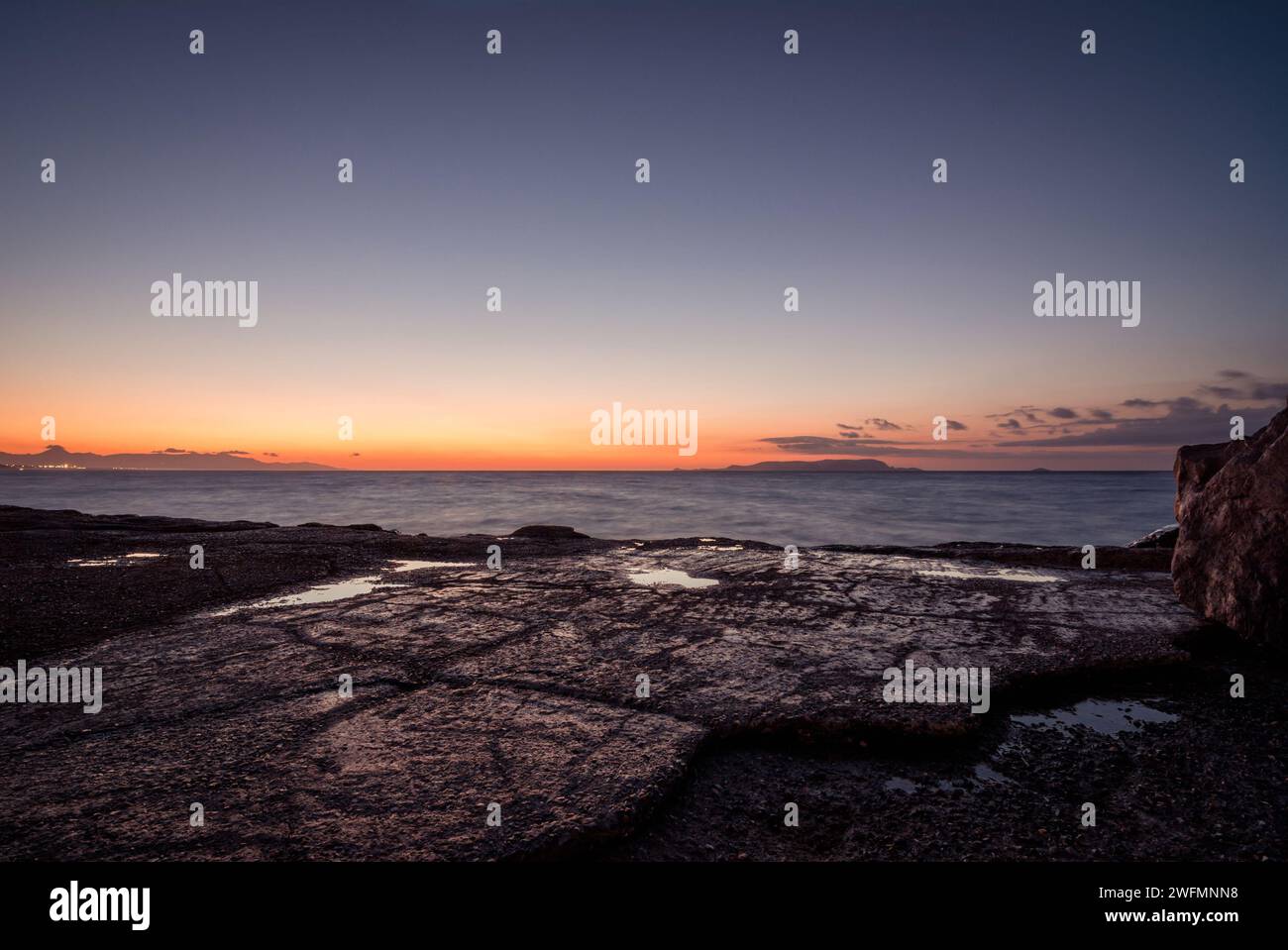 Smooth sea at dusk - long exposure shot with blurred waves. Wet rocks ...
