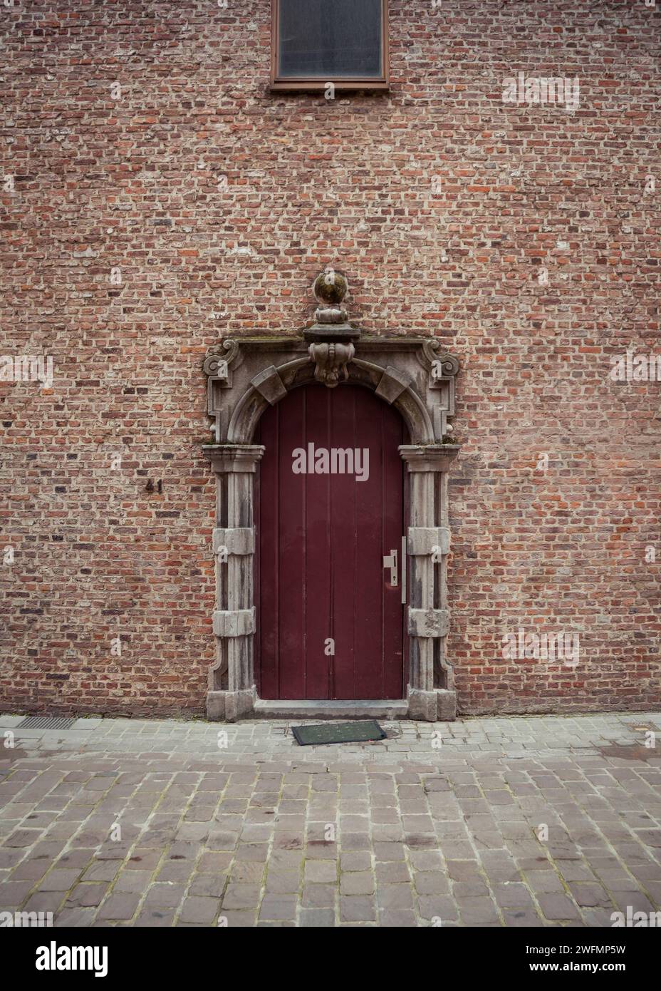 Brick wall with maroon-brown door. Facade of stone castle or house wall ...