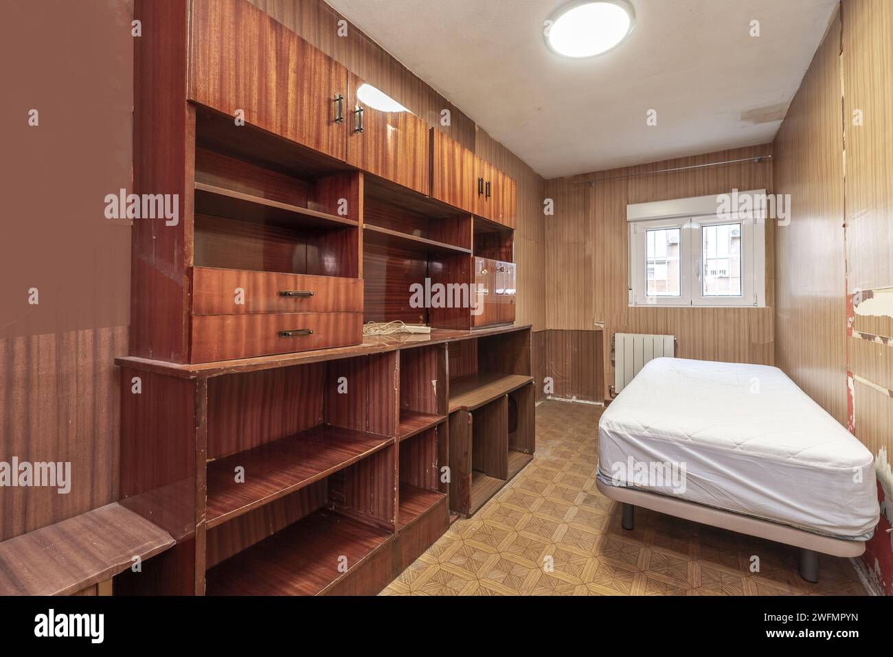 a gloomy room with brown walls with a rickety bookcase made of scrap ...