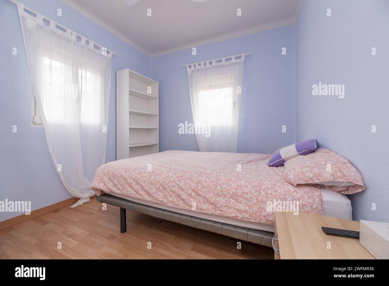 A double bedroom with pale blue walls and translucent white curtains on ...