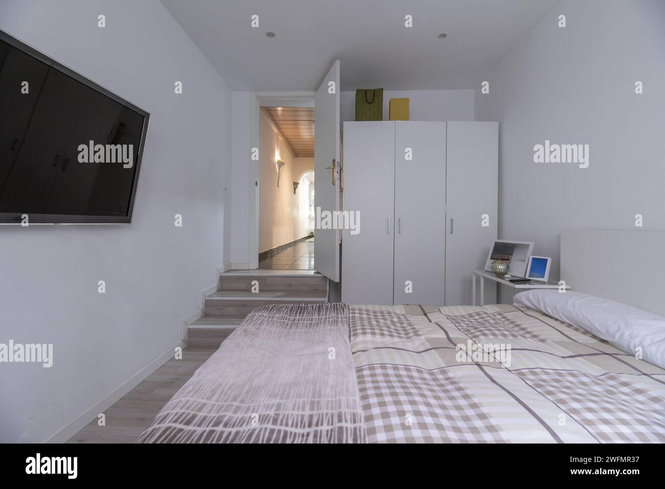 A double bedroom with white walls, a three-piece white wardrobe and a ...