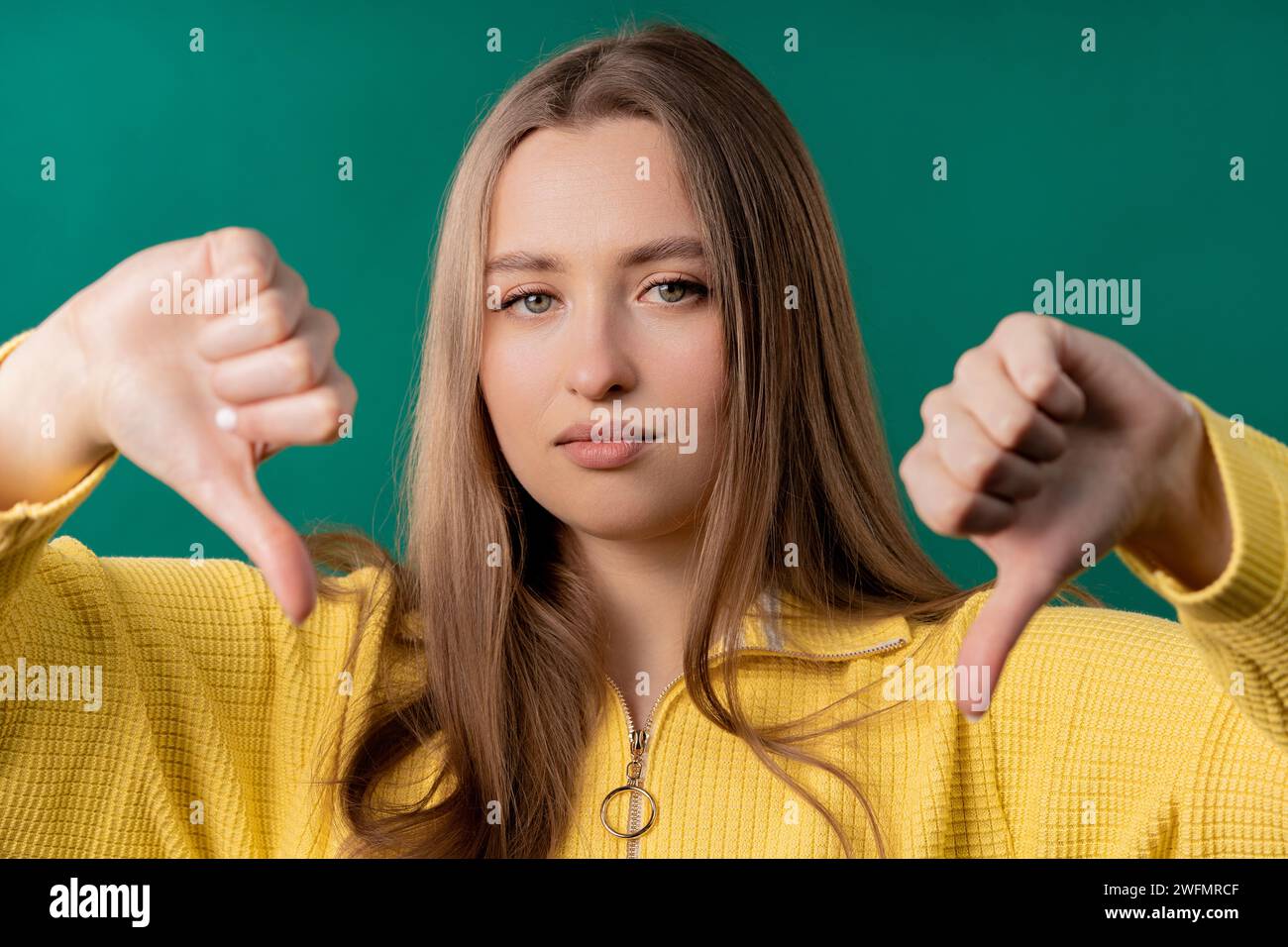 Pretty woman with sign of dislike. Young millennial girl showing thumbs ...