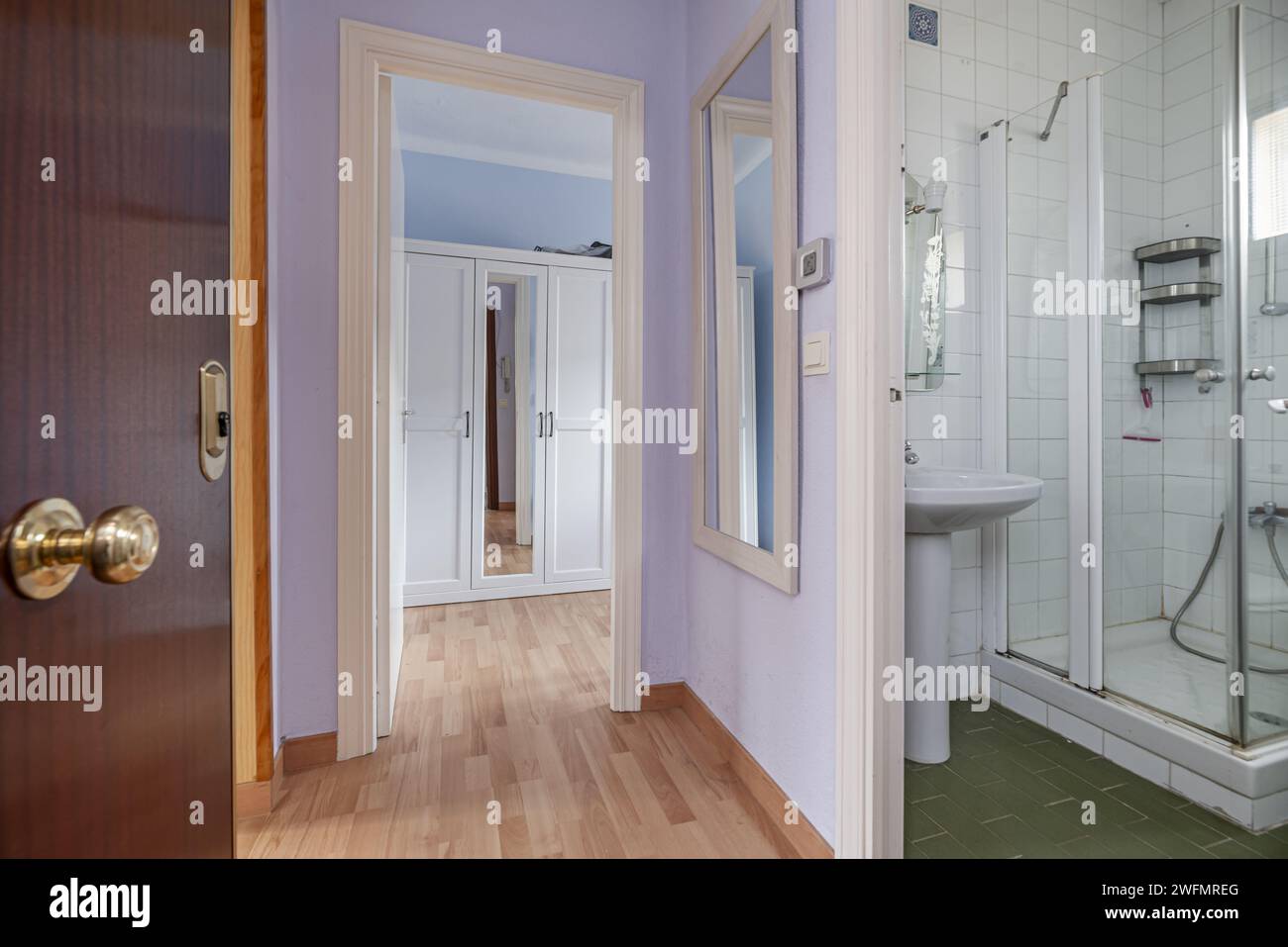 Hallway of a home with oak wood floors, smooth walls painted purple and ...
