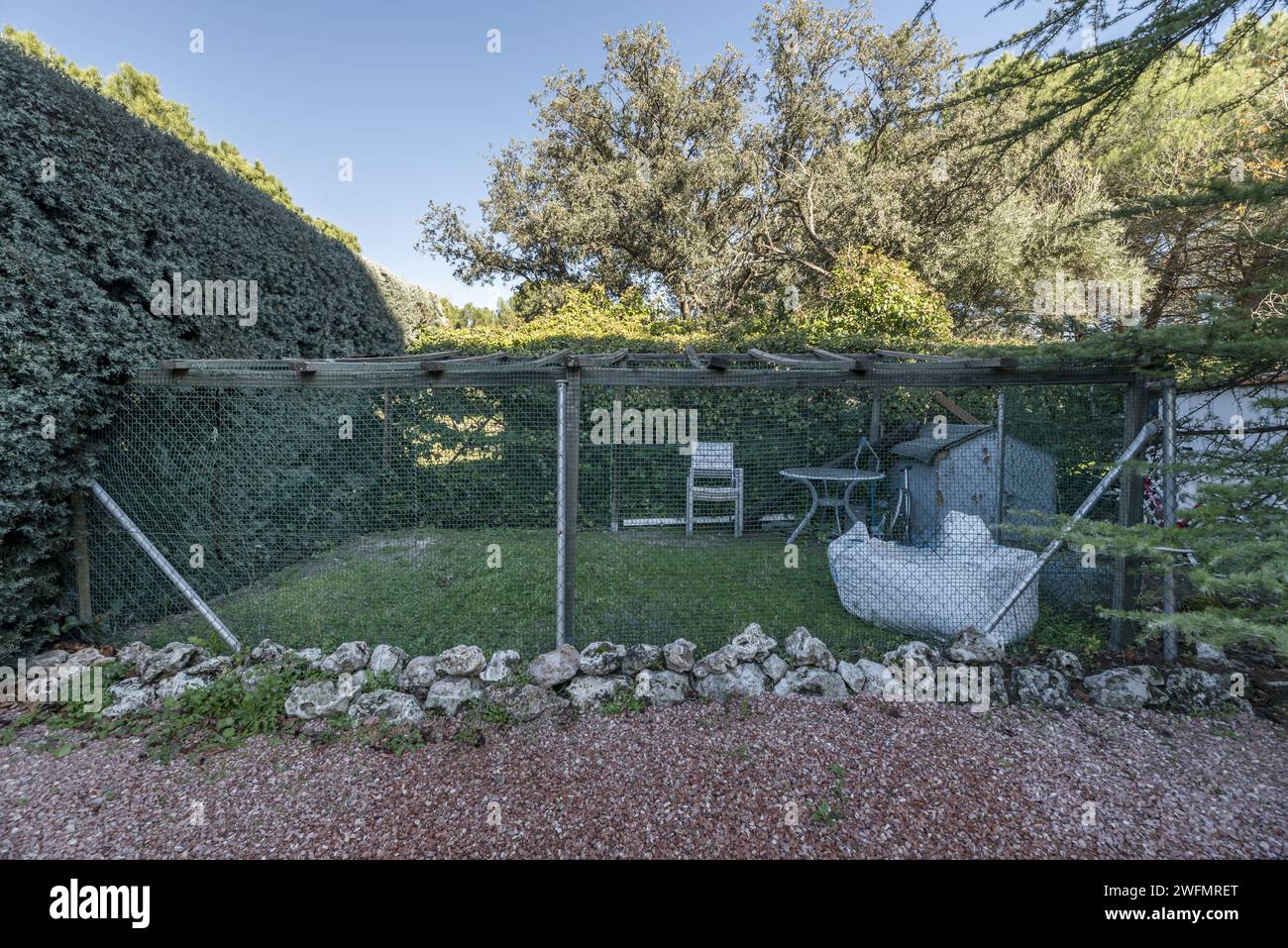 A bird breeding area with grids on fences and a roof within a farm with ...