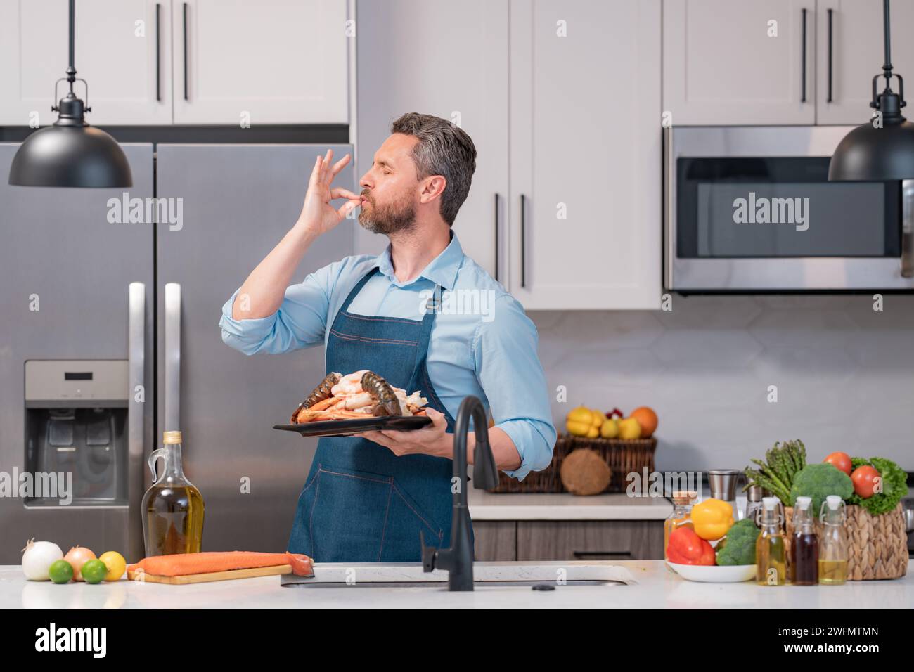 Man in cook apron preparing seafood at home modern kitchen. Man chefs ...