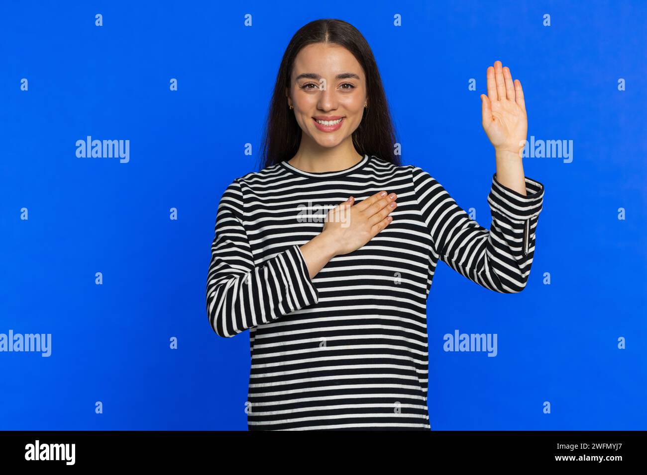 I swear to be honest. Sincere responsible smiling woman raising hand to ...