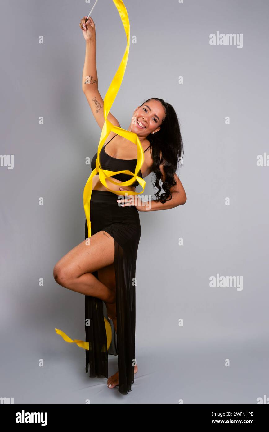 Beautiful gymnast woman doing acrobatic moves with a yellow ribbon ...