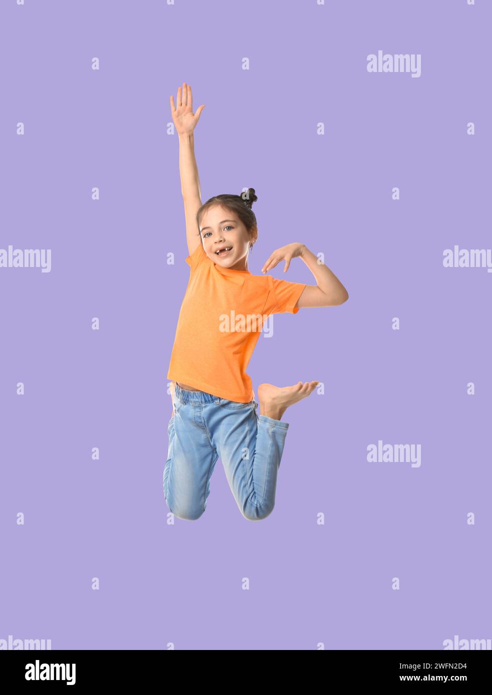 Happy cute girl jumping on light violet background Stock Photo - Alamy