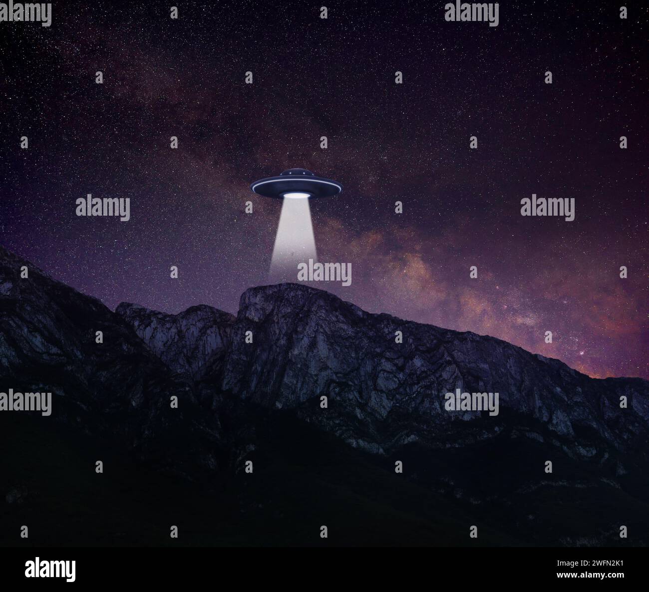 UFO. Alien spaceship emitting light beam over mountains ...