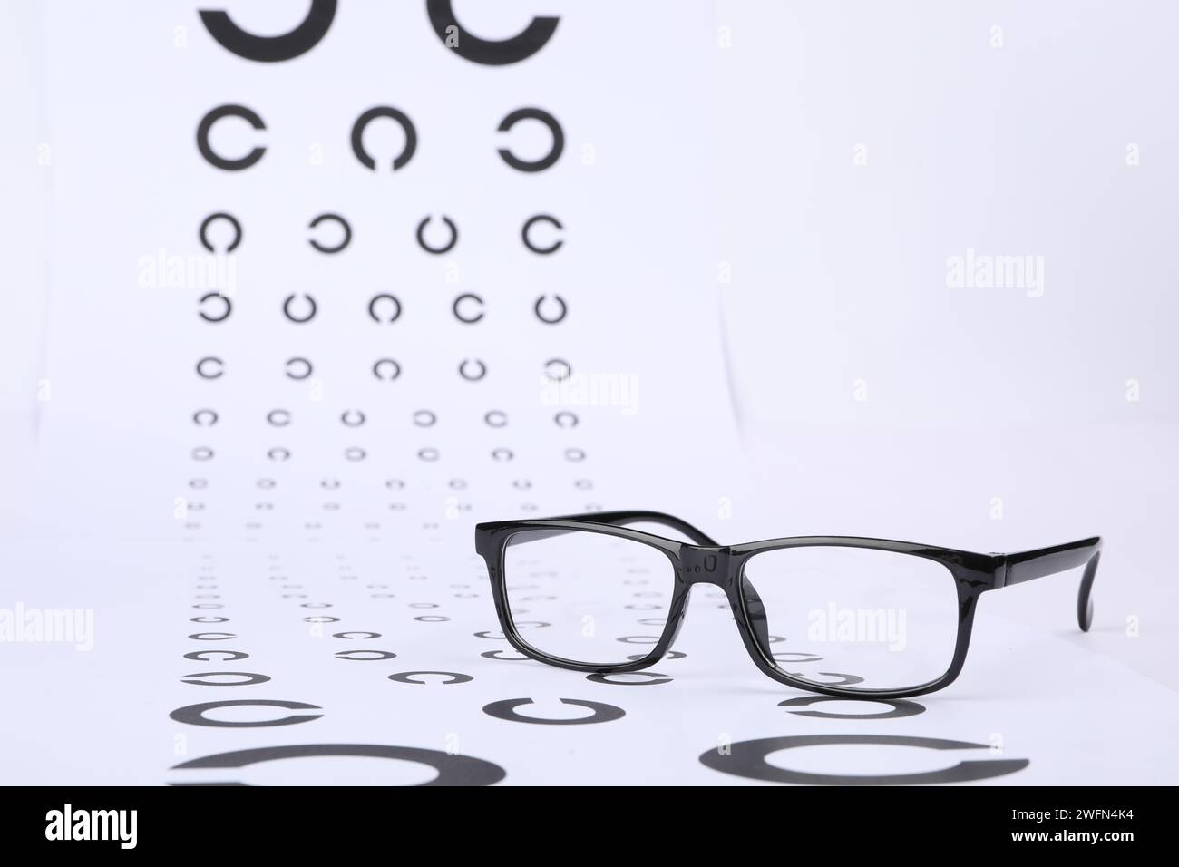 Vision test chart and glasses on white background, closeup. Space for ...