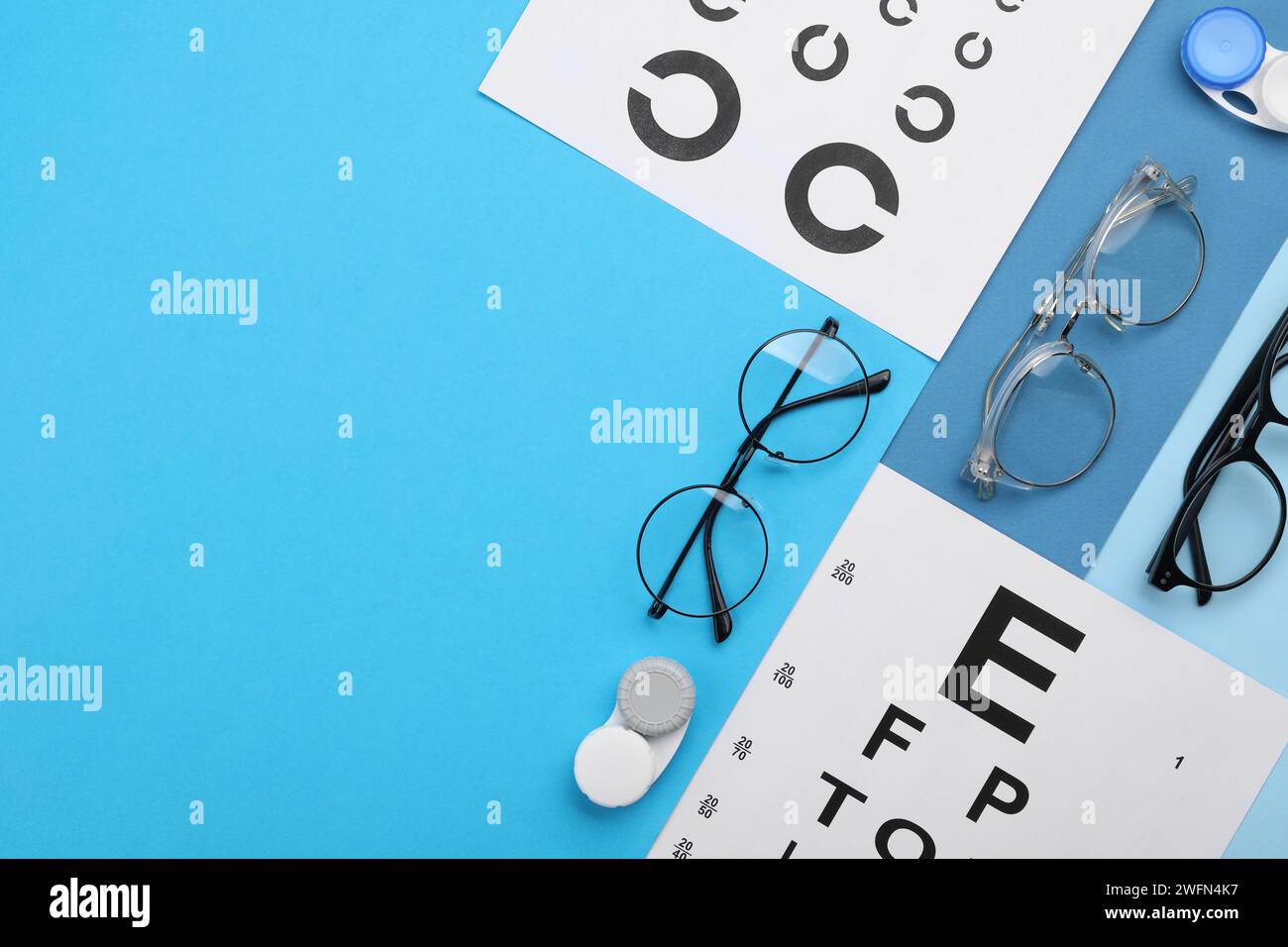 Vision test charts, glasses and lenses on light blue background, flat ...