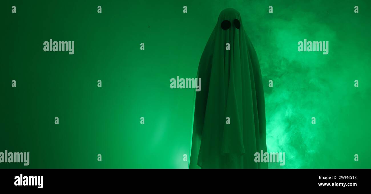 Creepy ghost. Woman covered with sheet in green light, space for text ...