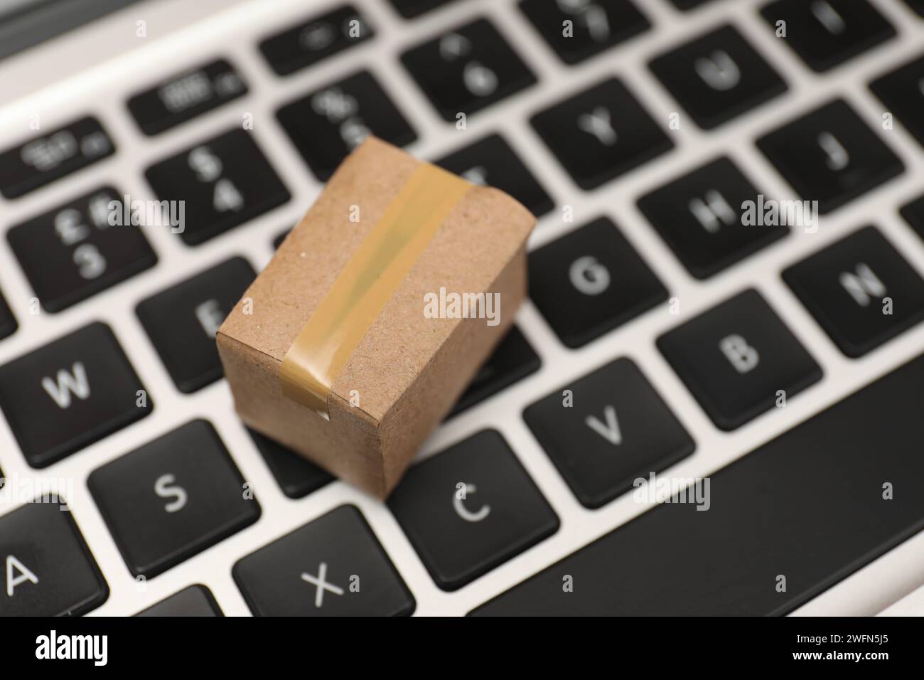 Internet shopping. Small cardboard box on laptop, closeup. Space for ...