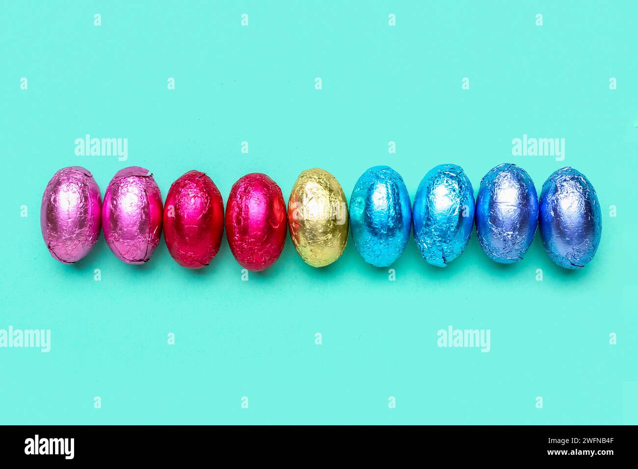 Row of chocolate Easter eggs in foil on color background Stock Photo ...