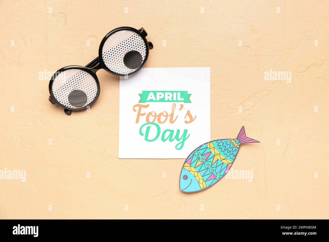 Paper with text APRIL FOOL'S DAY, fish and funny eyeglasses on beige ...