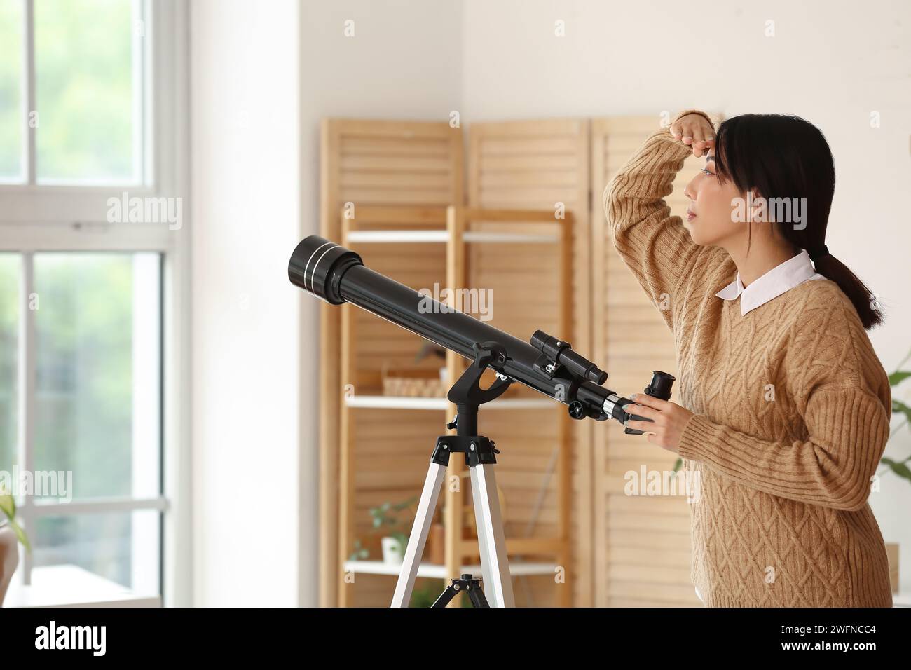 Young Asian woman using telescope at home Stock Photo - Alamy