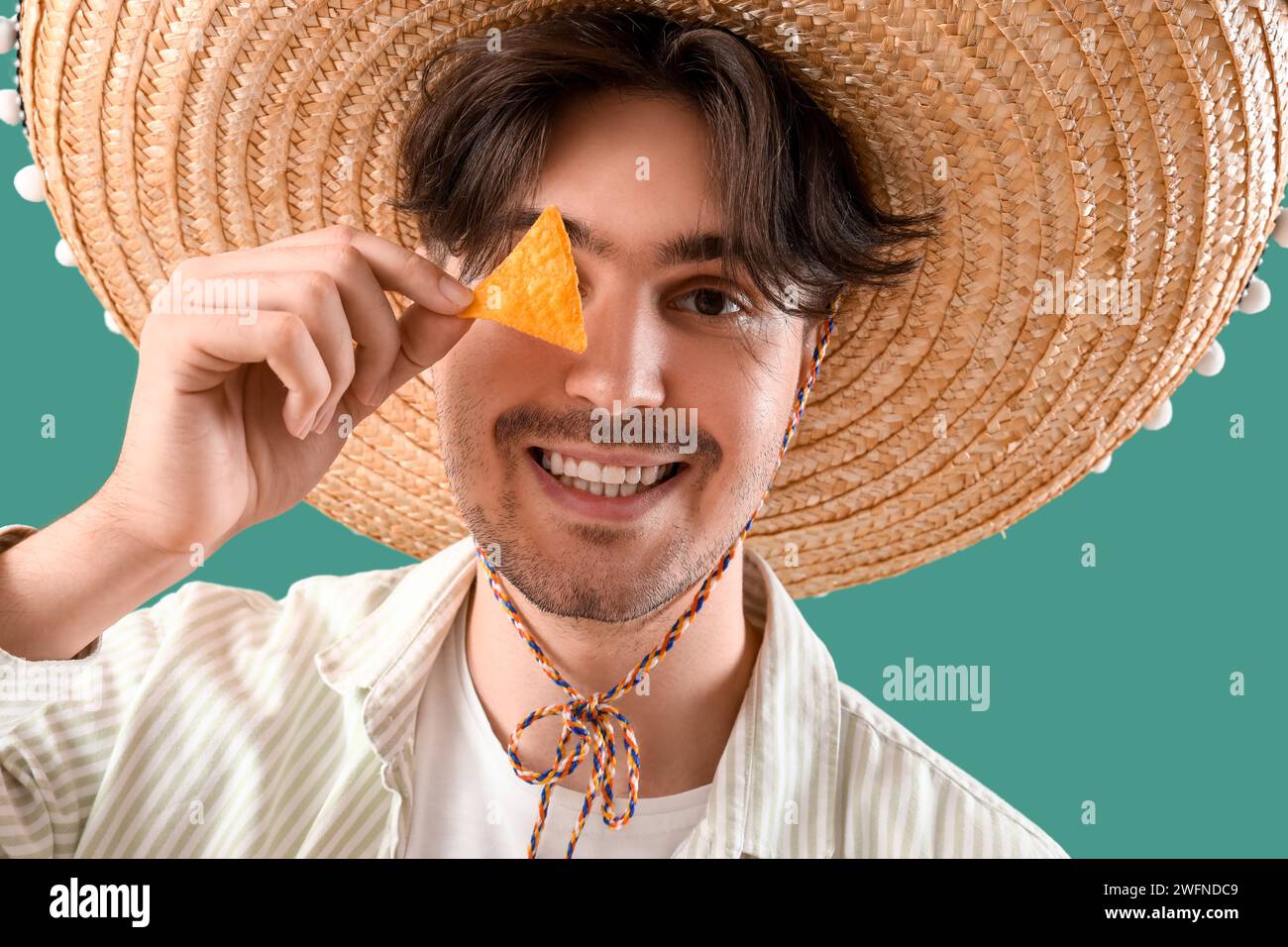 Young Mexican man with nachos on green background Stock Photo - Alamy