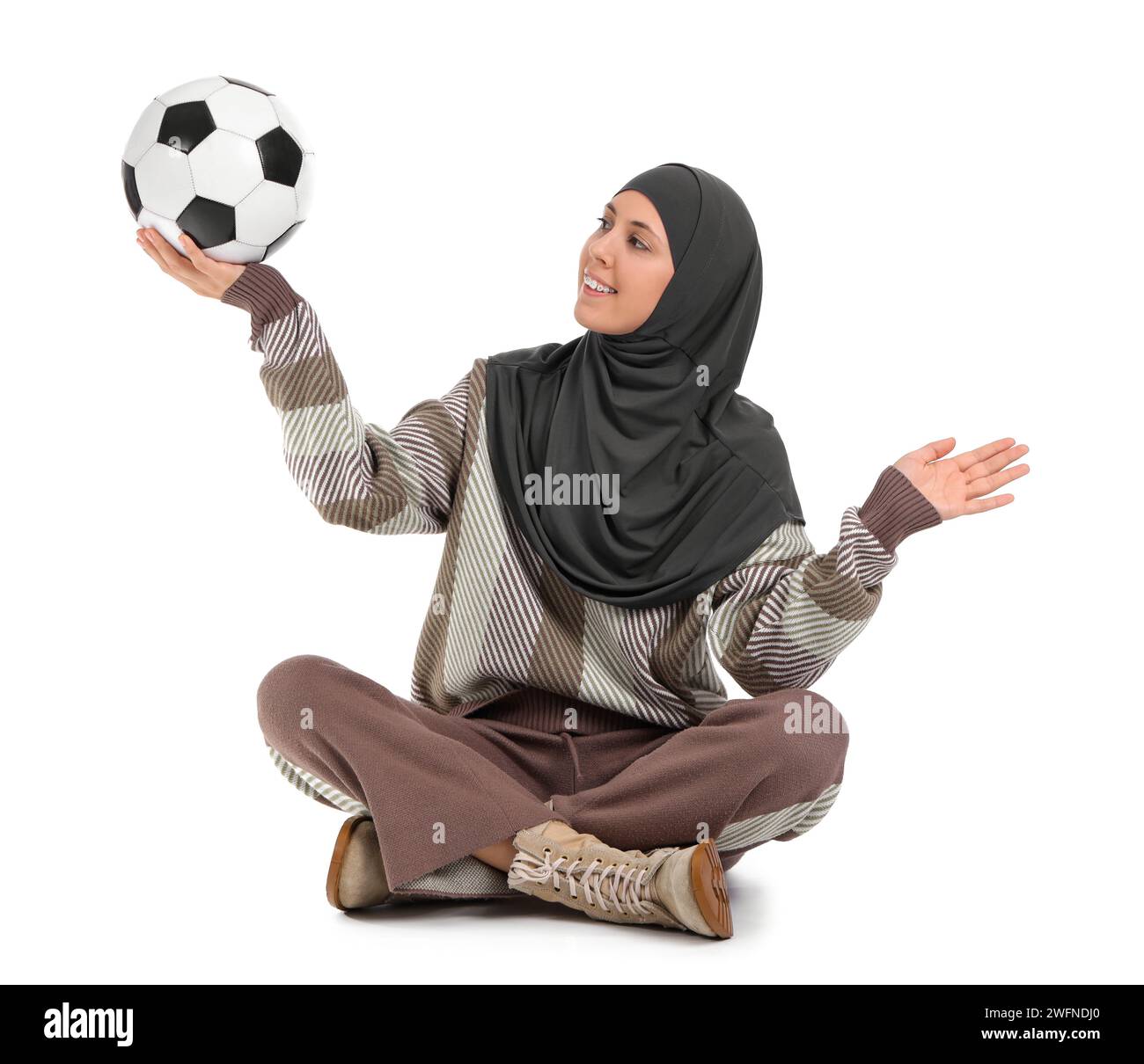 Young beautiful Muslim woman in hijab with soccer ball sitting on white ...