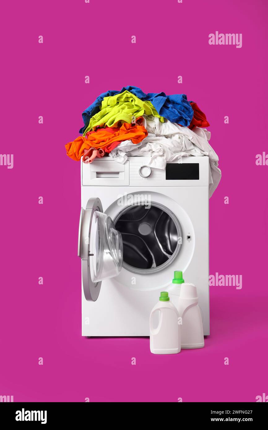 Washing machine with laundry and detergents on magenta background Stock ...