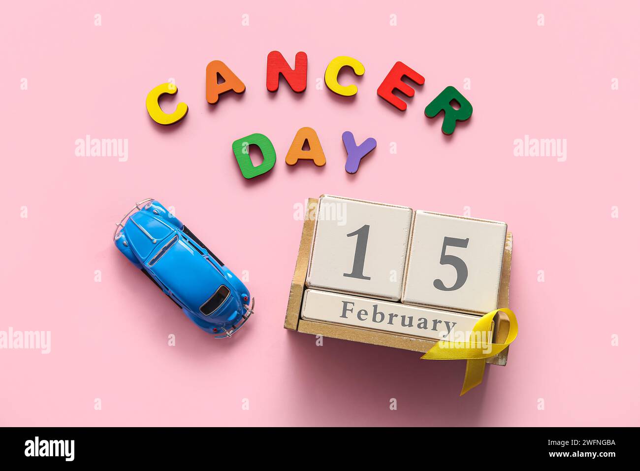 Words CANCER DAY with calendar, golden ribbon and toy car on pink ...