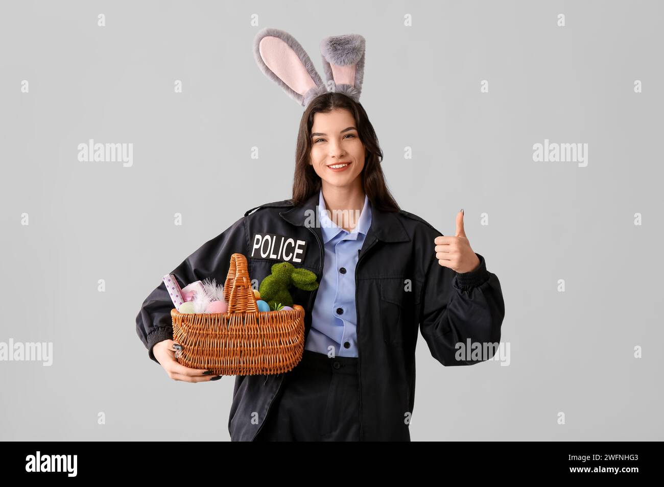 Female police officer in bunny ears with Easter eggs showing thumb-up ...