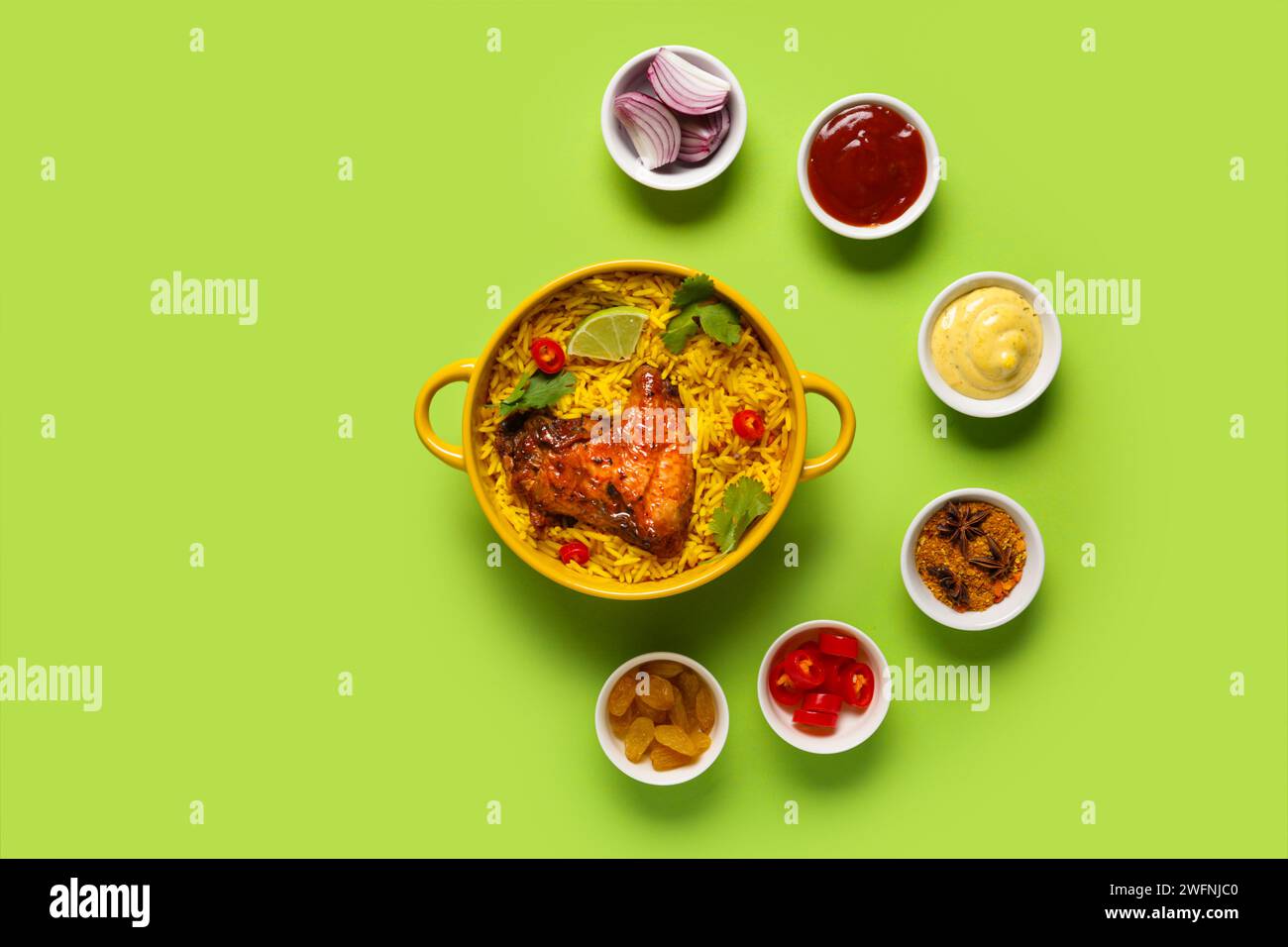 Bowl of traditional chicken biryani with ingredients on green ...