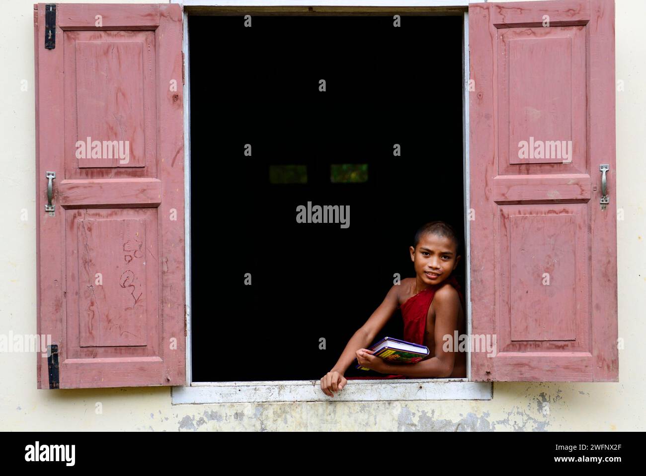 Young Buddhist monks looking out the monastery window in Mrauk-U ...