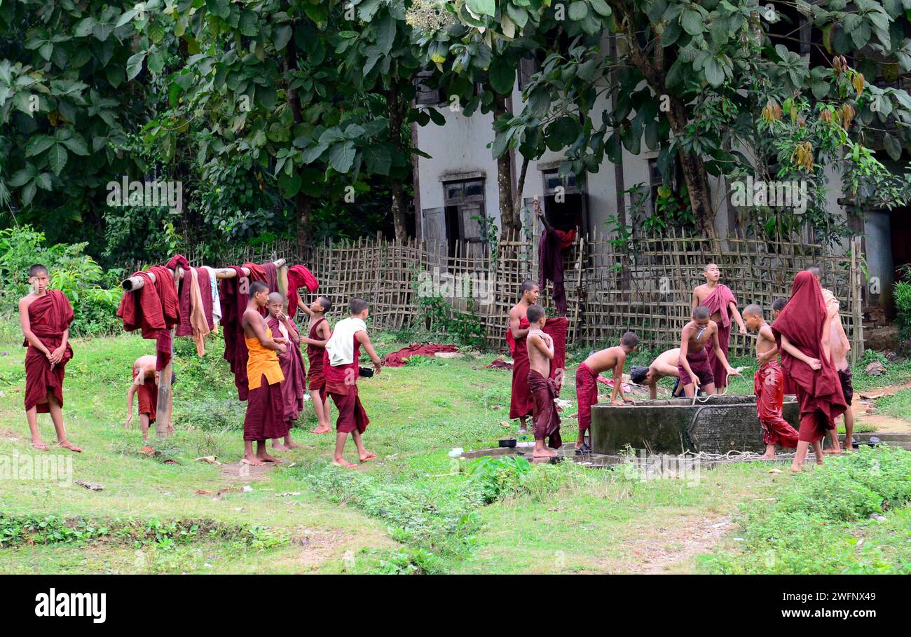 Young Buddhist monks washing with water from an open well in Mrauk U ...