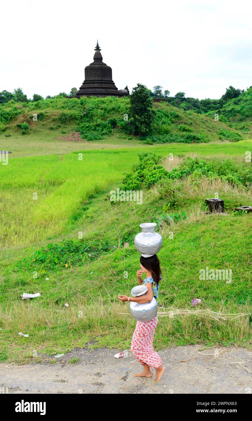 An Arakanese woman carrying water jugs back to their village in Mrauk-U ...